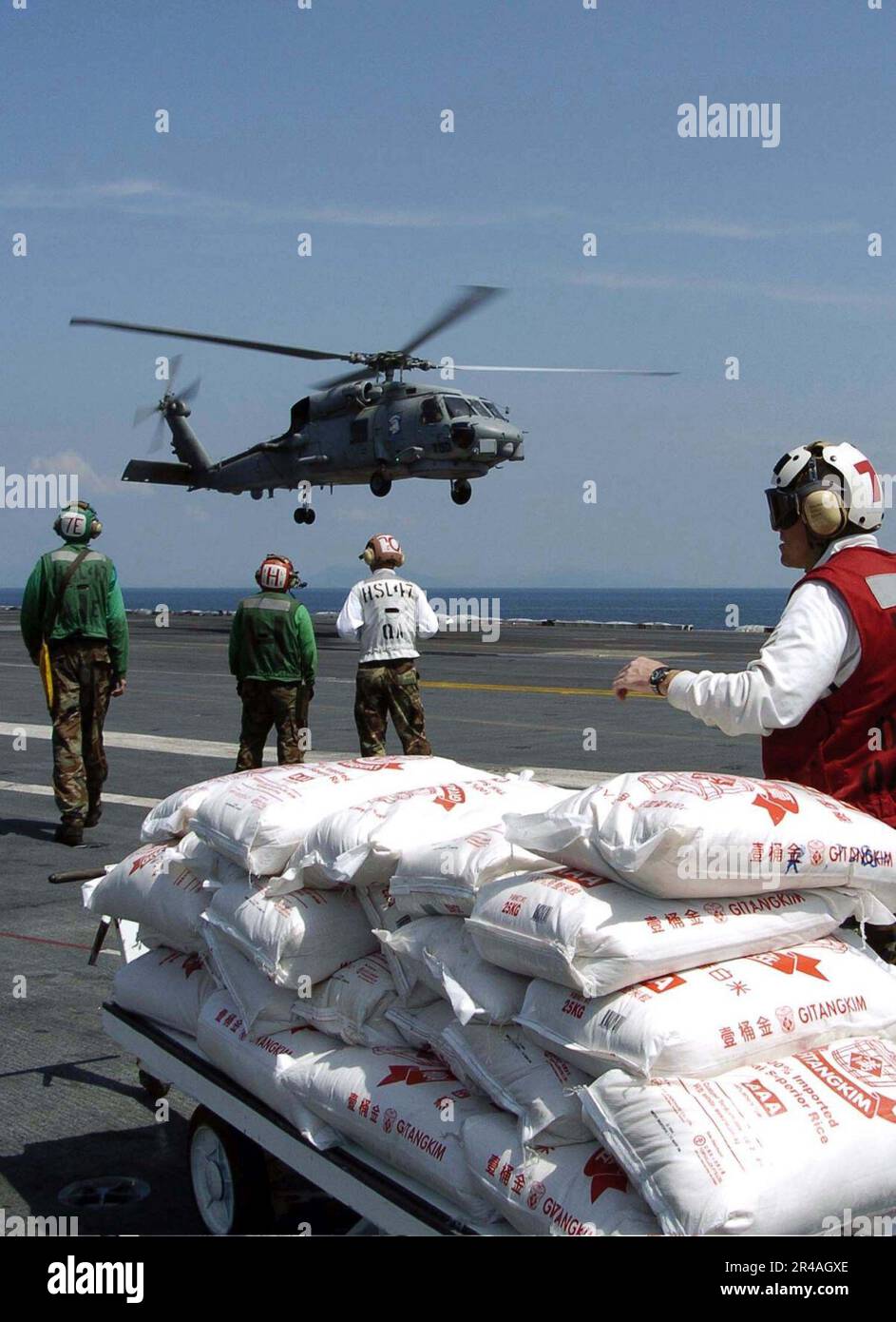 US Navy Bags of rice wait to be loaded onto an SH-60B Seahawk ...