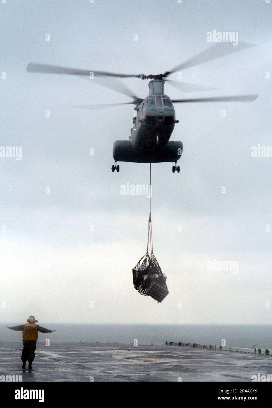 US Navy A Marine Corps CH-46 Sea Knight helicopter carrying supplies, approaches the flight deck ...