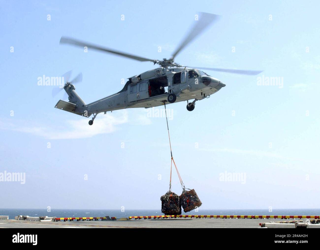 US Navy An MH-60S Knighthawk helicopter lifts off with a cargo net of ...