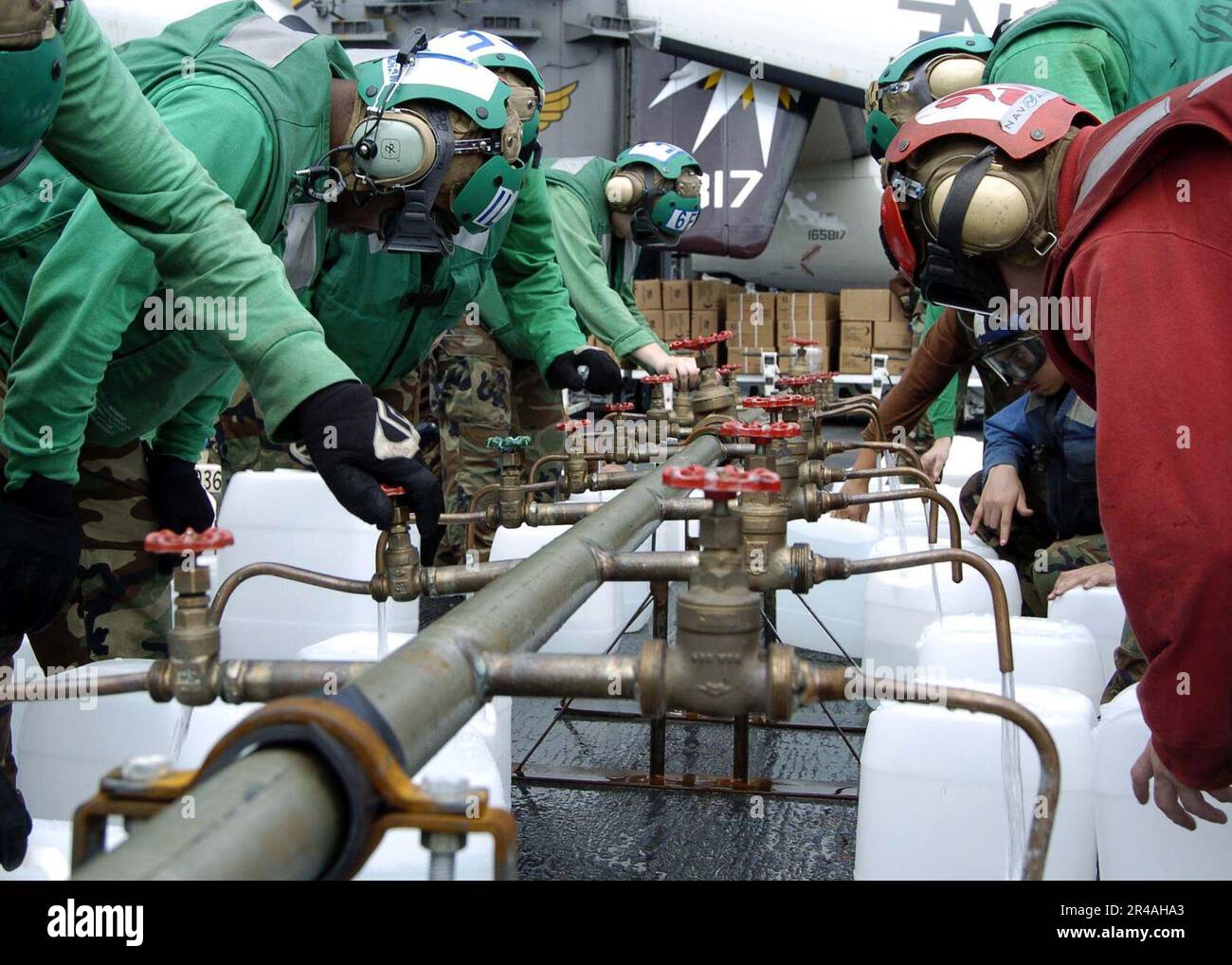 US Navy Crew members aboard USS Abraham Lincoln (CVN 72) fill jugs with ...