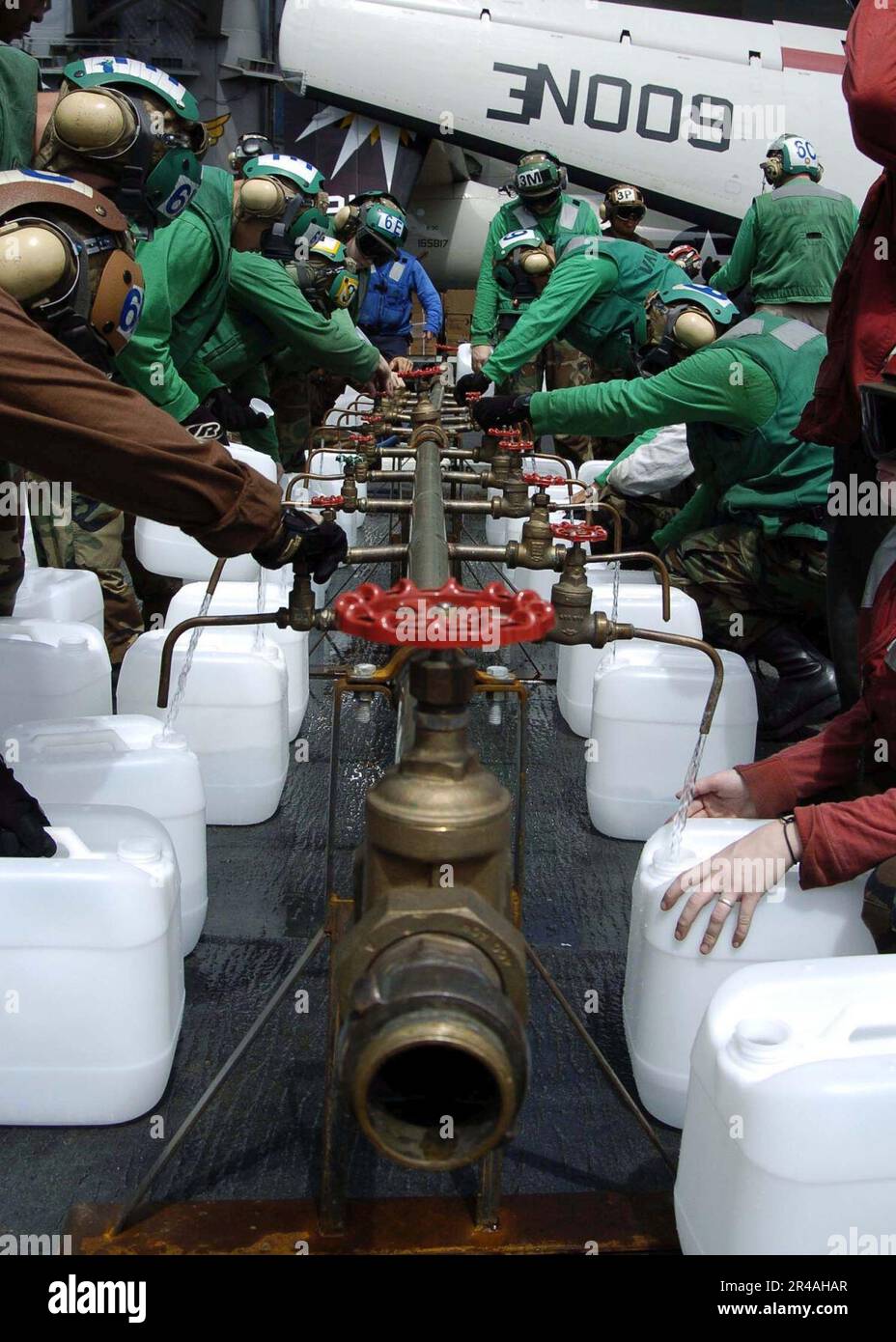US Navy Crew members aboard USS Abraham Lincoln (CVN 72) fill jugs with ...