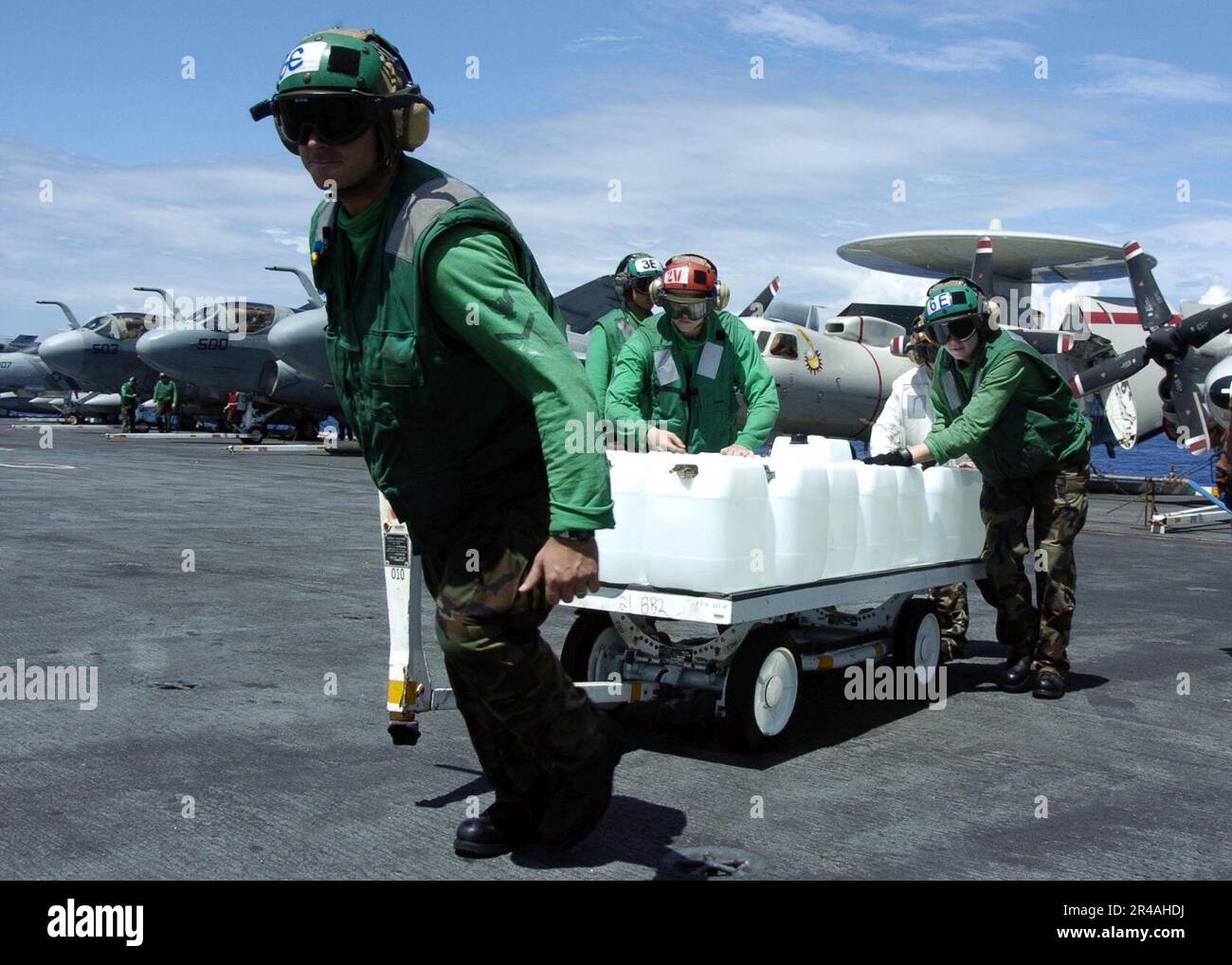 US Navy Flight deck personnel transport a weapons skid full of purified ...
