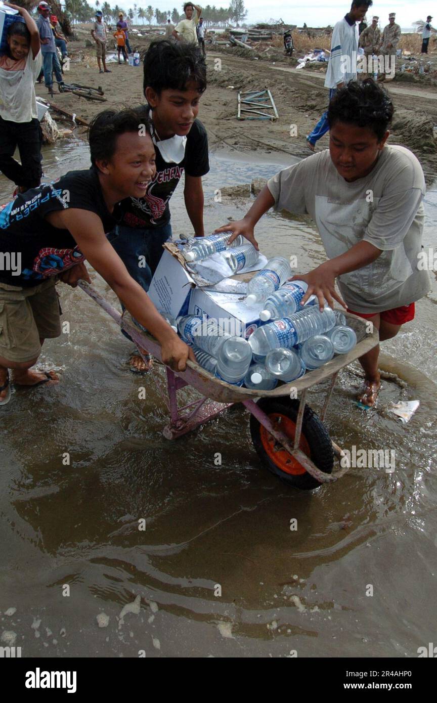 US Navy Indonesian kids carry bottles of drinking water in a ...