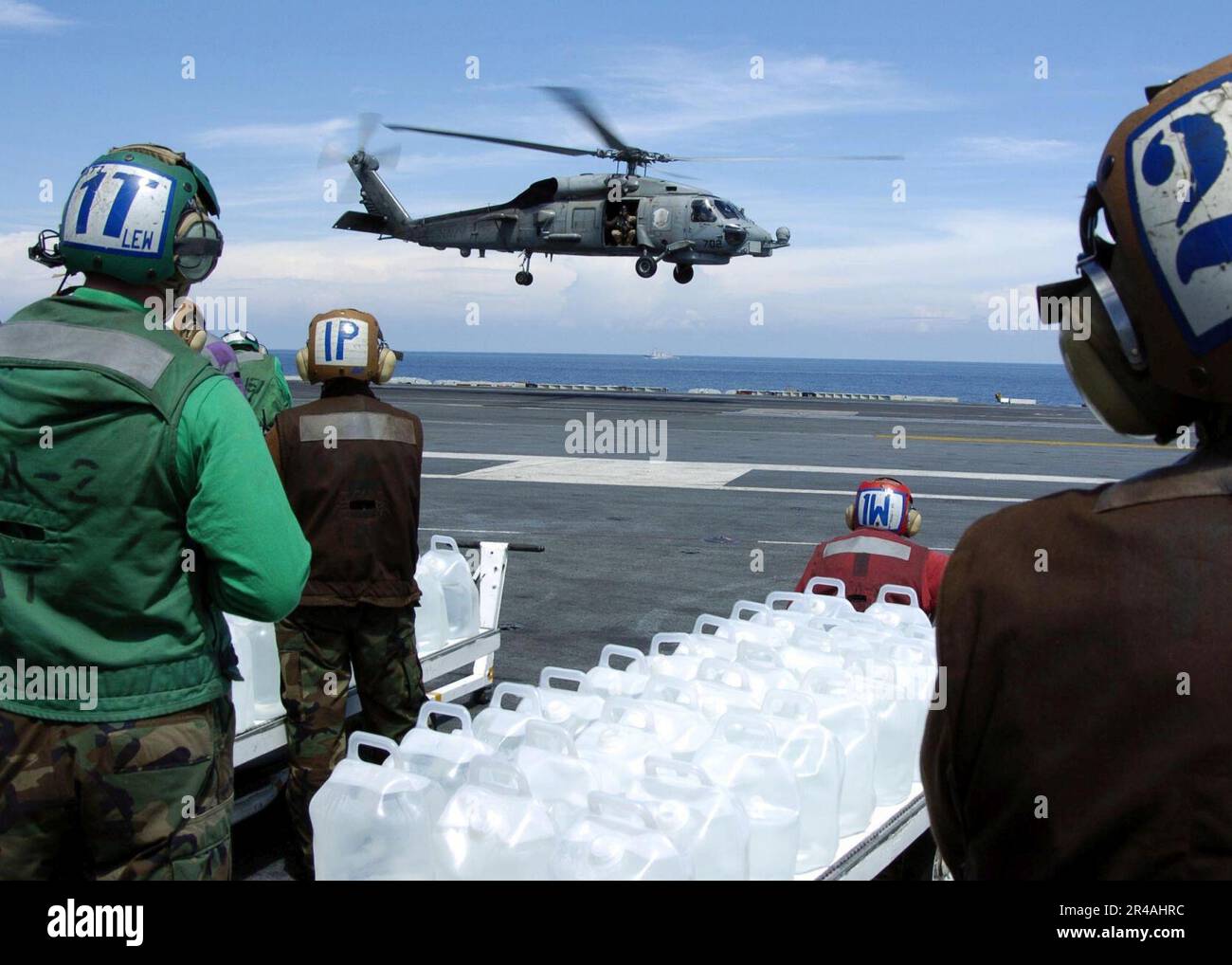 US Navy Sailors stand-by to load jugs of purified water into an ...
