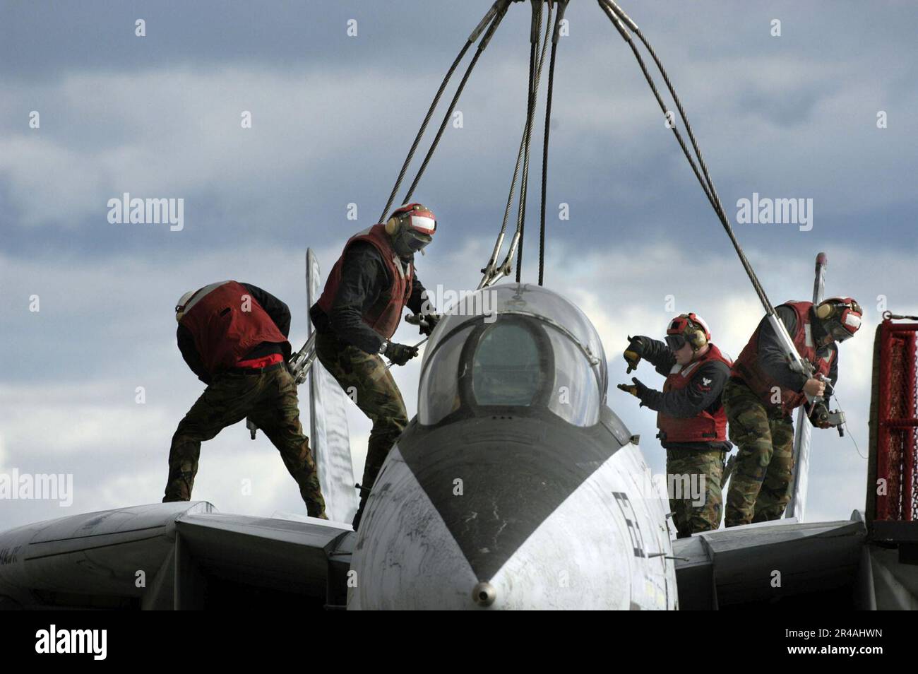 US Navy Crash-and-salvage personnel connect rigging cables to a F-14 ...