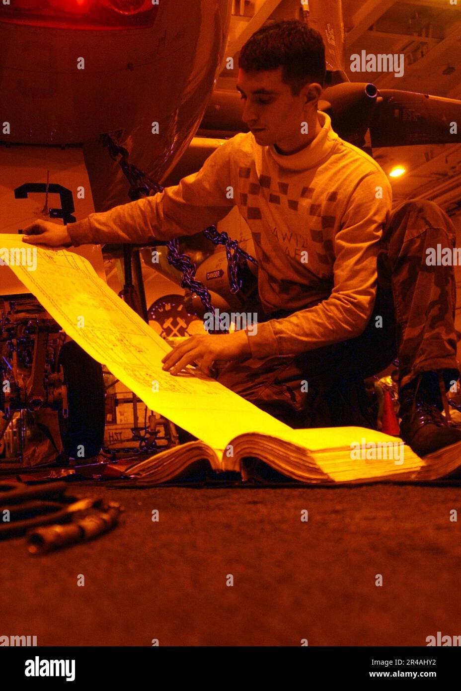 US Navy Aviation Structural Mechanic 1st Class studies a wire diagram ...