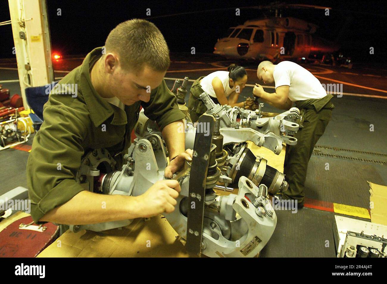 US Navy Sailors perform maintance on MH-60 Knighthawk rotor blade parts ...