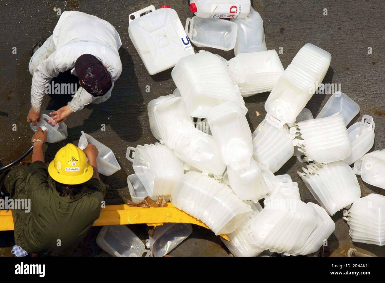 US Navy Merchant Marine Sailors fill water containers aboard the ...