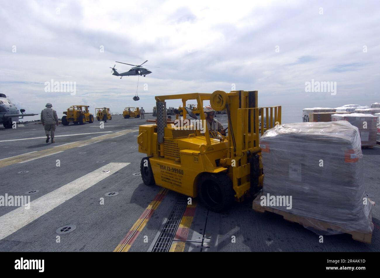 US Navy A Marine drives a forklift filled with supplies aboard the ...