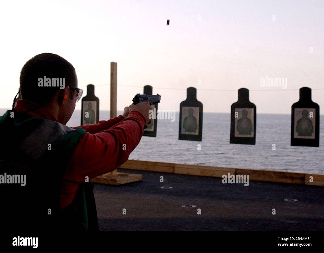 US Navy A Sailor shoots a 9mm handgun at a target during a live-fire ...