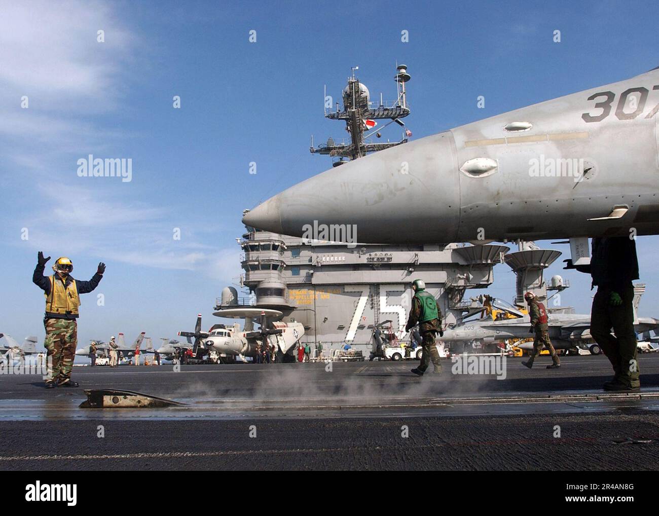 US Navy Sailors assigned to the Air Department help guide a taxiing F-A ...