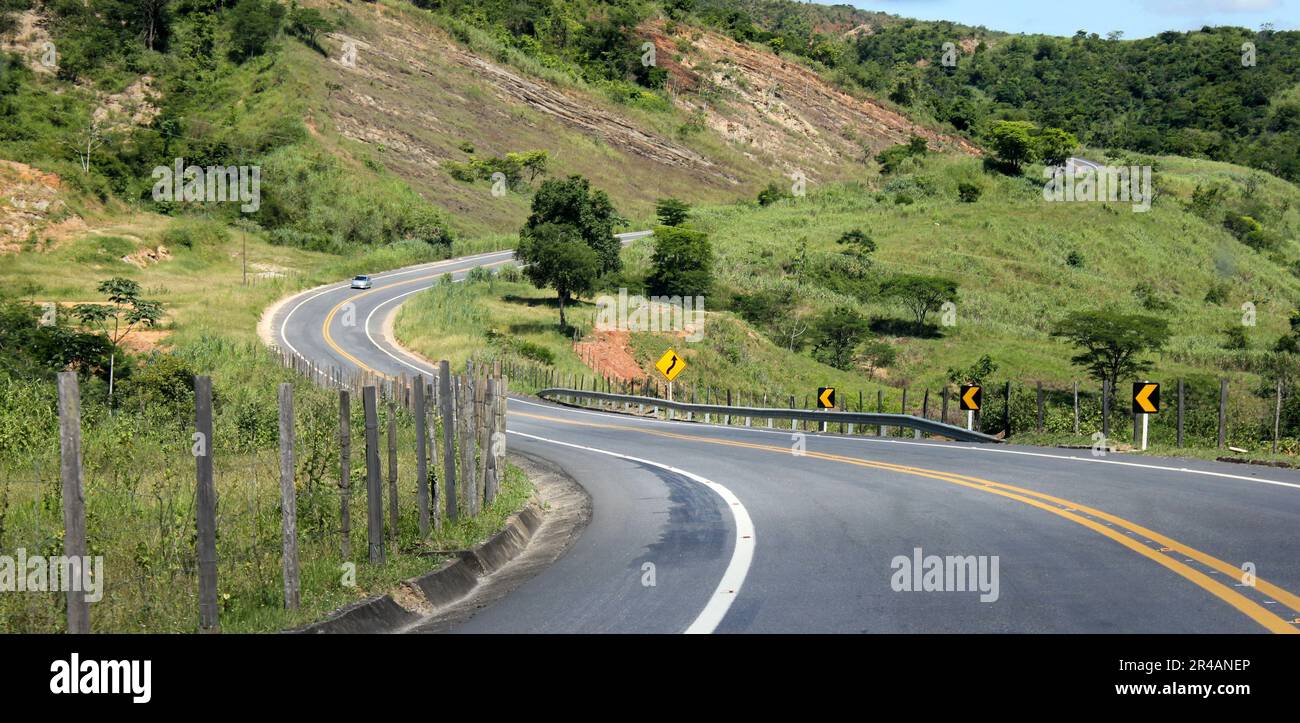 A scenic road in Brazil shows successive vertical signs with arrows ...