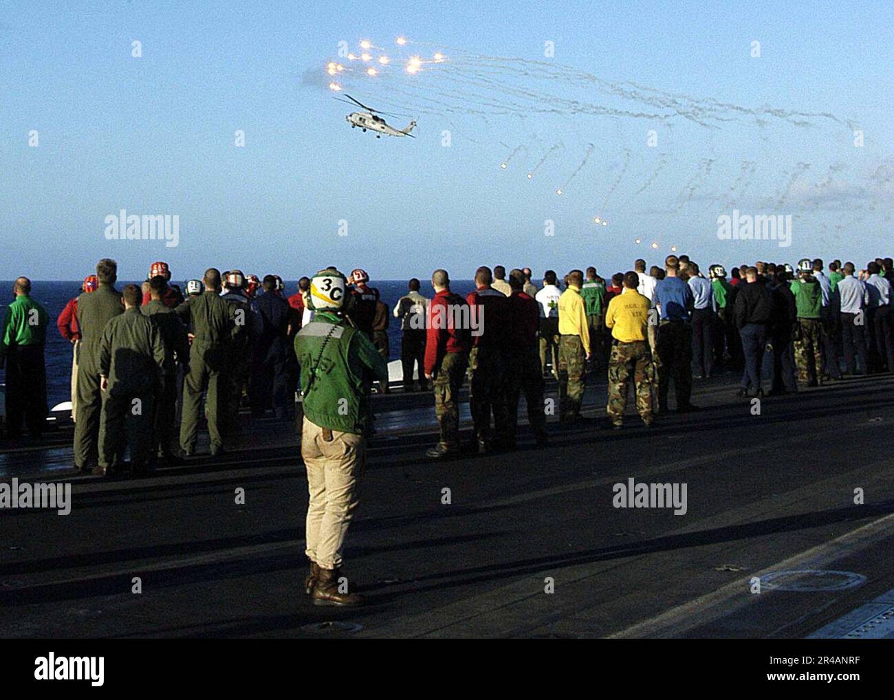 US Navy Sailors watch as a SH-60F Seahawk helicopter releases flares ...