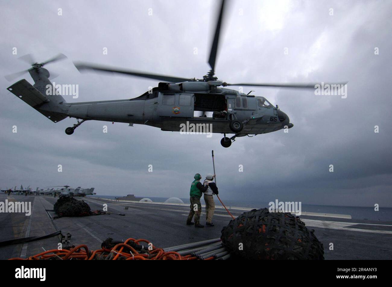 US Navy Supply personnel connect a cargo pendant to an MH-60S Seahawk ...