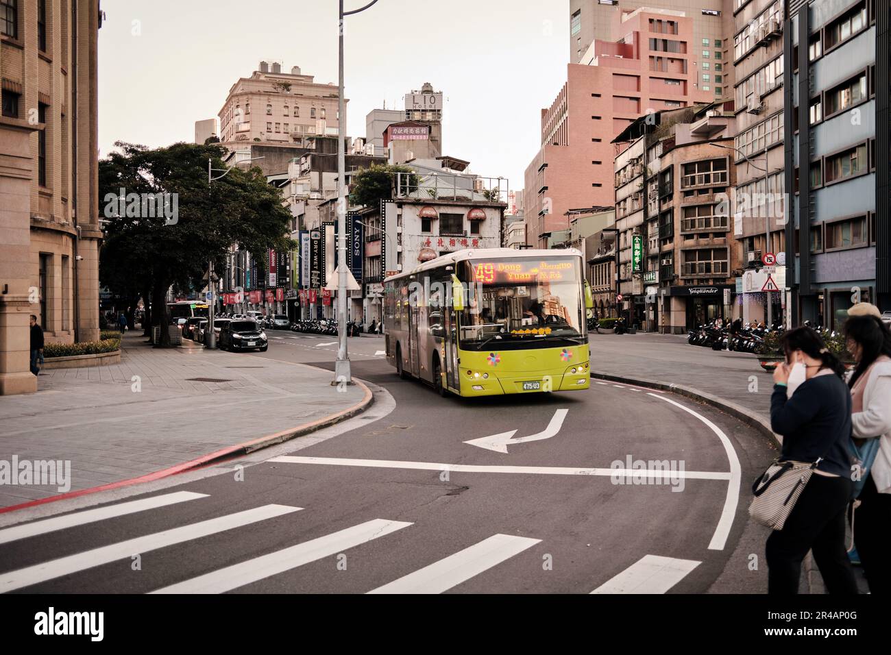 A diverse group of pedestrians waiting to cross a busy urban street as ...
