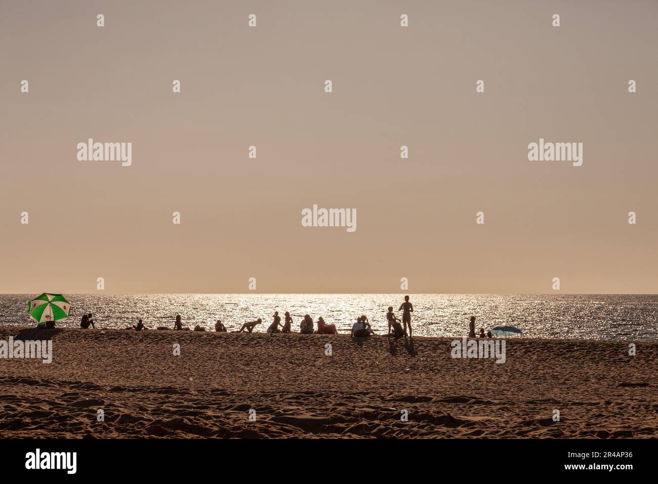 Silhouettes of people on the beach at sunset. Luanda Beach, Angola ...