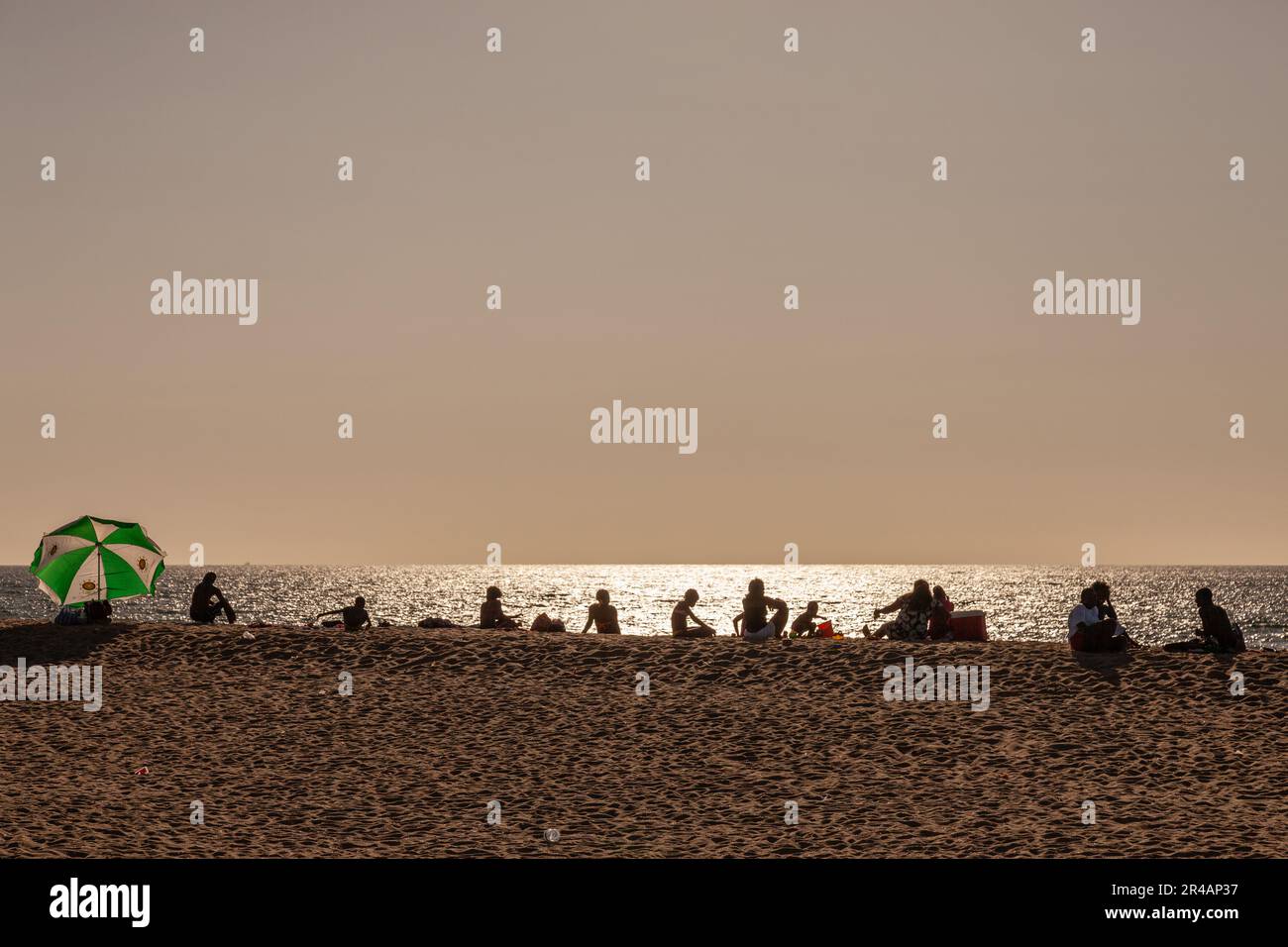 Silhouettes of people on the beach at sunset. Luanda Beach, Angola ...