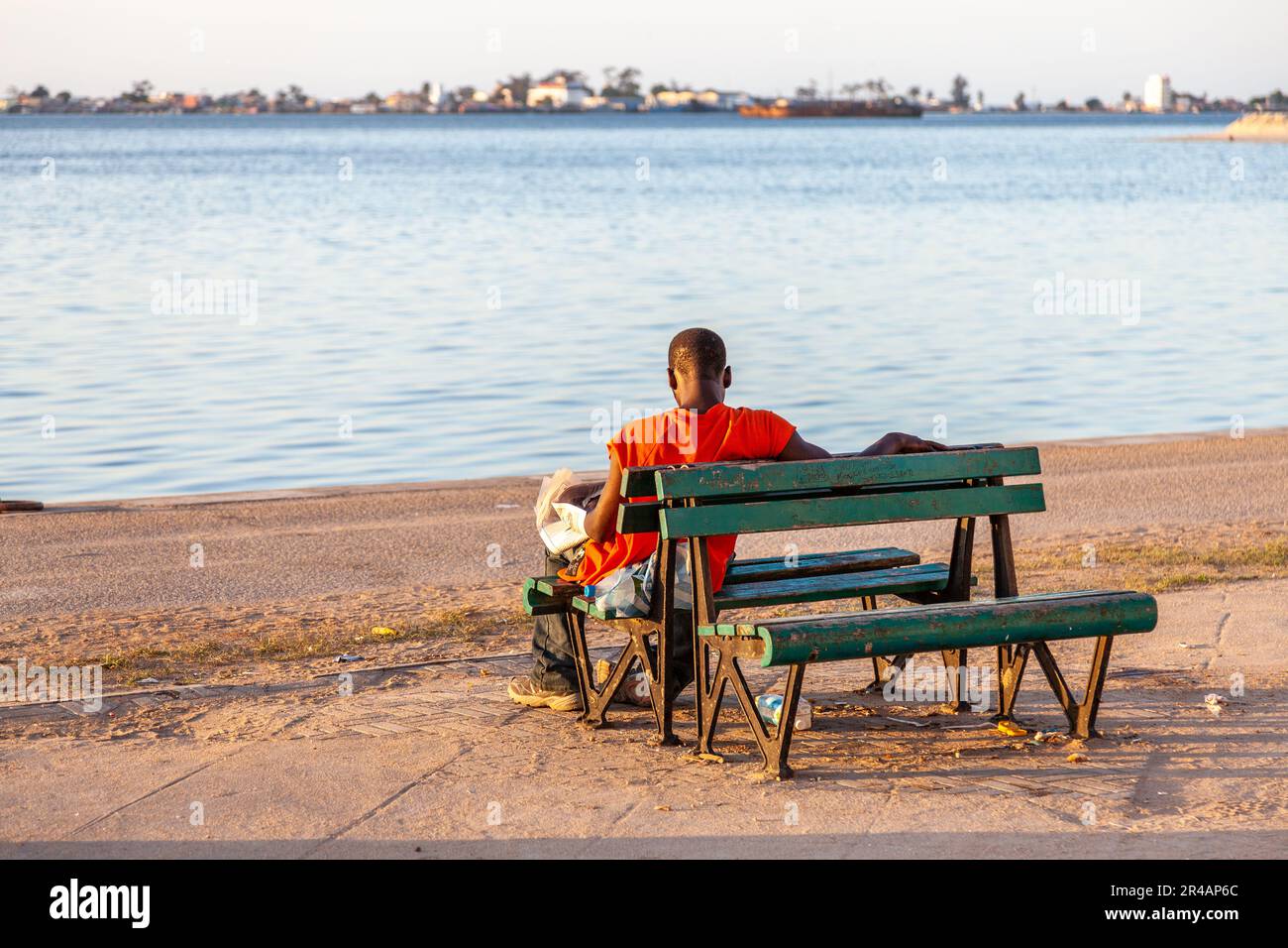 Man sitting in front of the sea, on a bench in the promenade of the bay ...