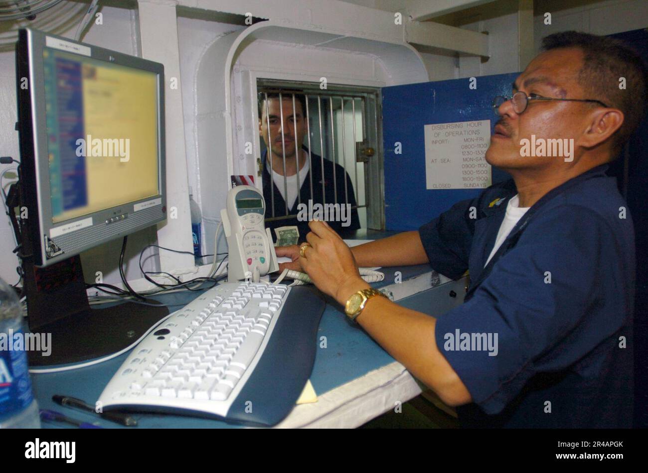US Navy Disbursing Clerk 1st Class checks the balance of a customer's ...