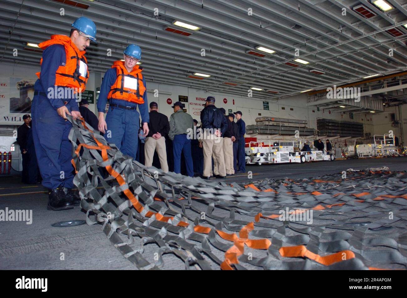 US Navy Two Sailors assigned to the Deck Department layout a cargo net ...