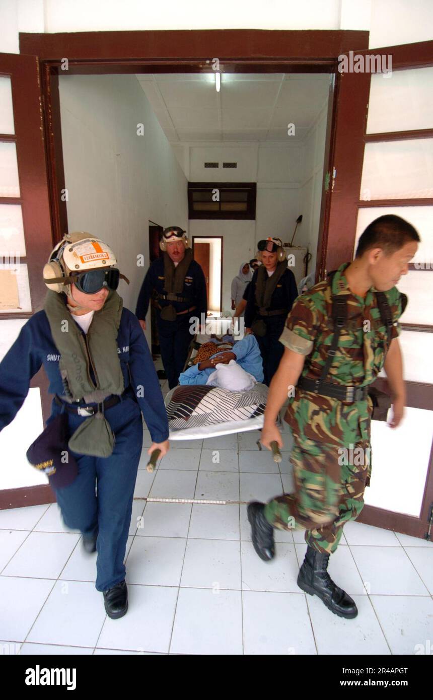 US Navy Medical personnel and an Indonesian Armed Forces member carry a ...