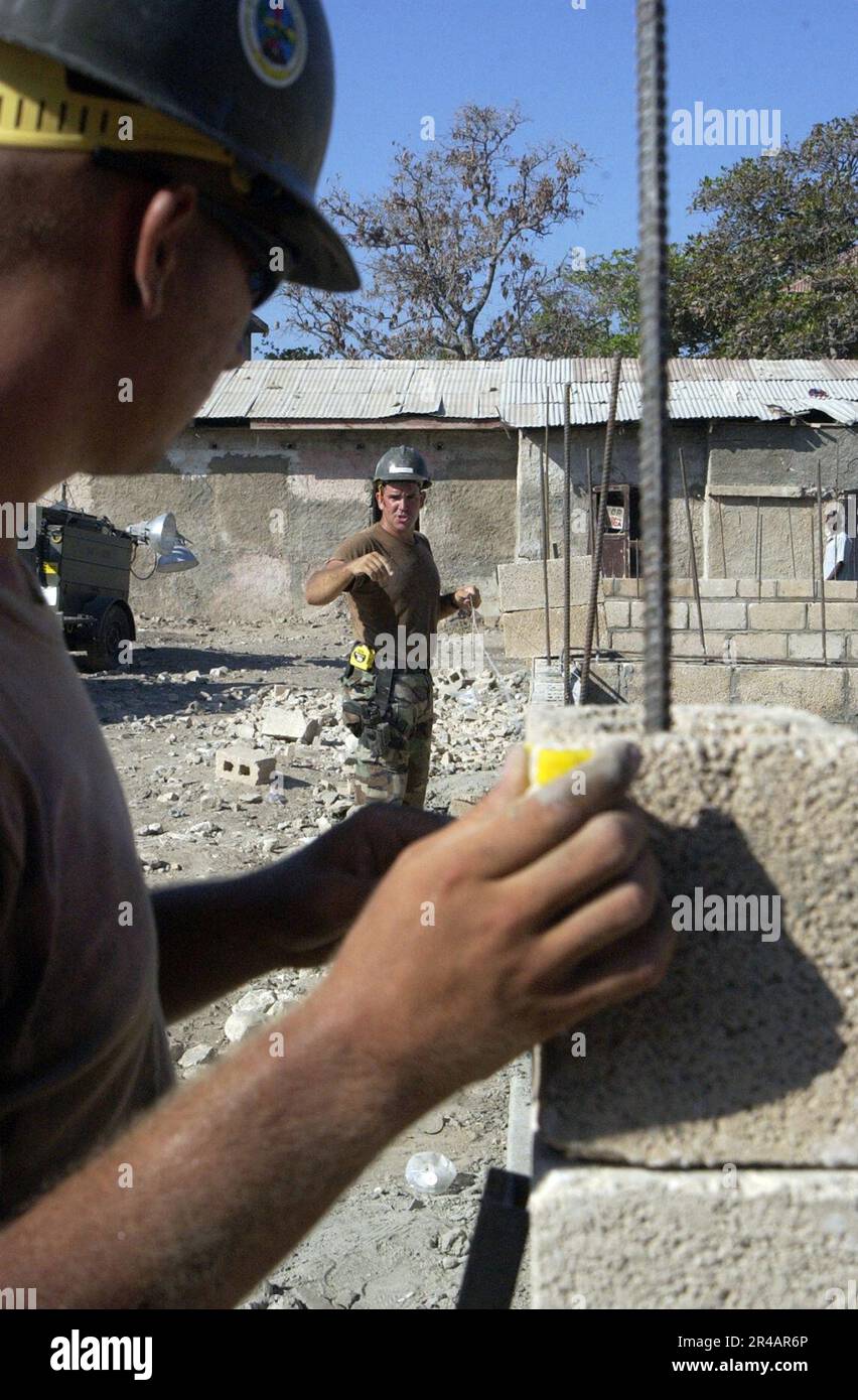 US Navy Builder Constructionman Apprentice foreground, holds the end of ...