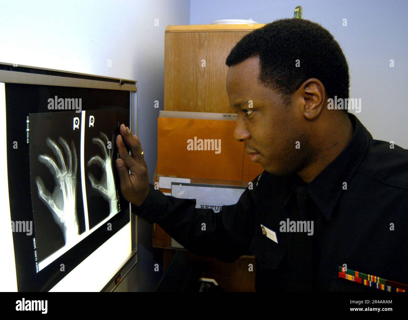US Navy Hospital Corpsman 3rd Class checks an X-ray of a patient's hand ...