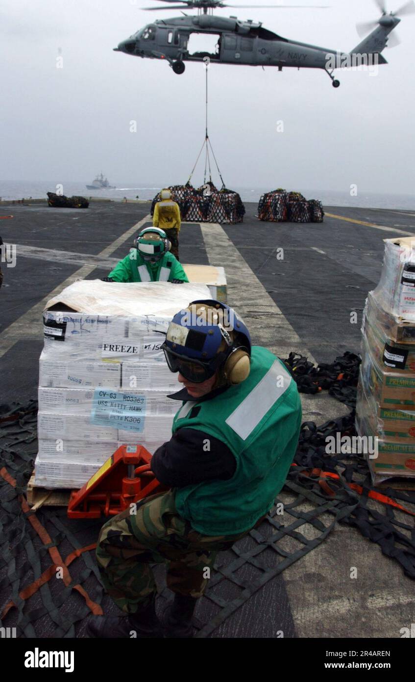 US Navy Storekeeper Seaman maneuvers supplies across the flight deck ...