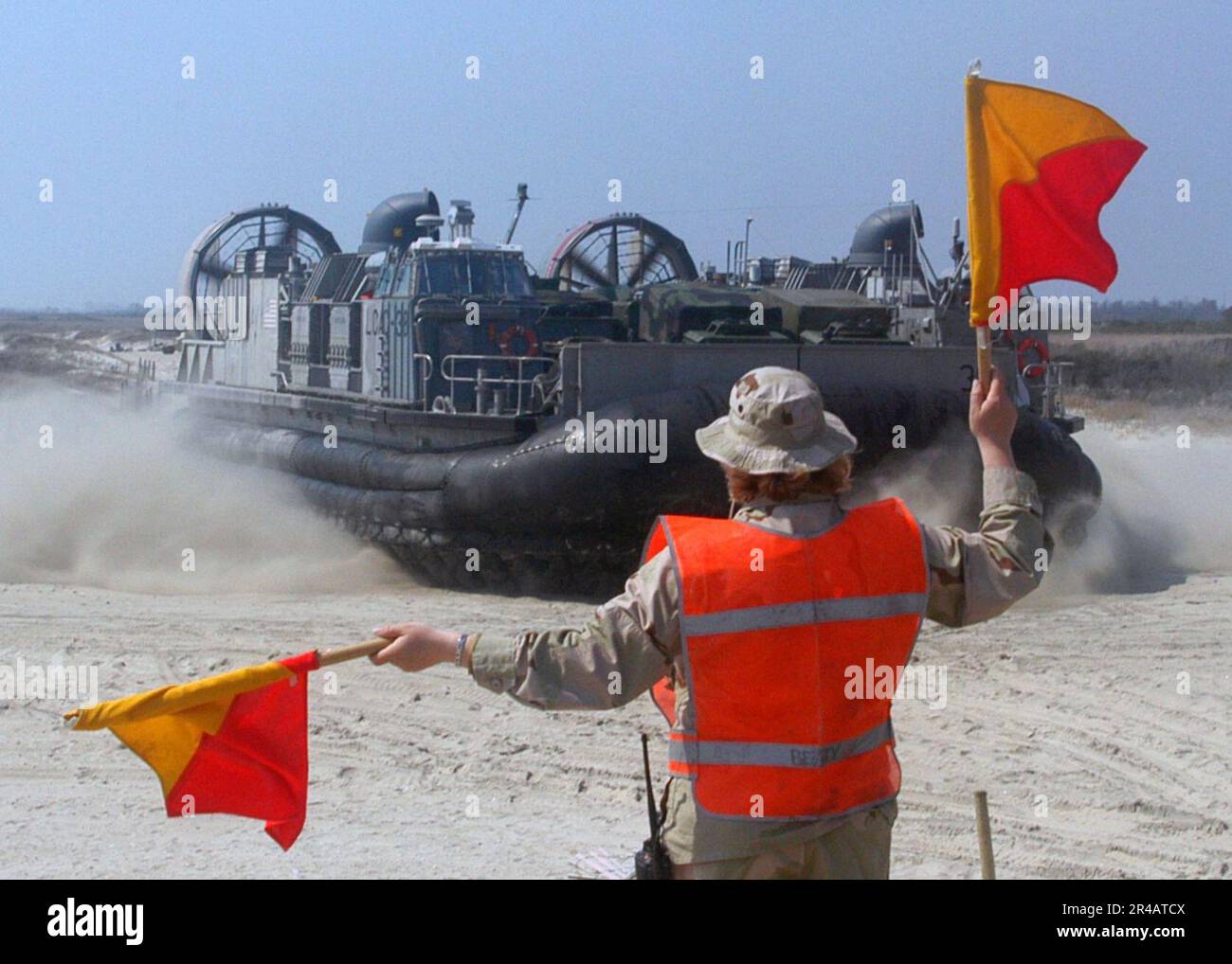 US Navy Beach Master, Seaman signals a Landing Craft, Air Cushion (LCAC ...