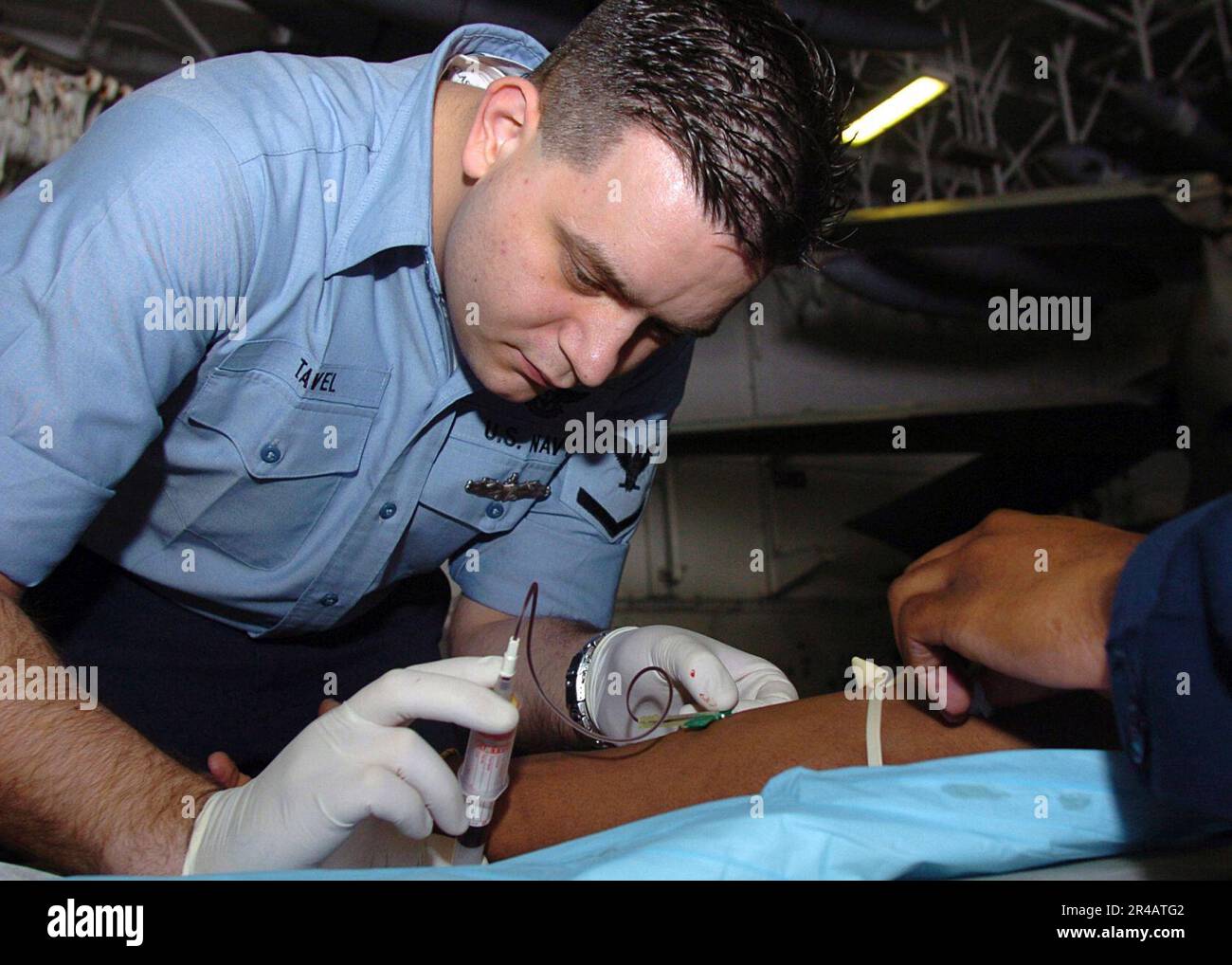 US Navy Hospital Corpsman 3rd Class draws a blood sample from a Sailor ...