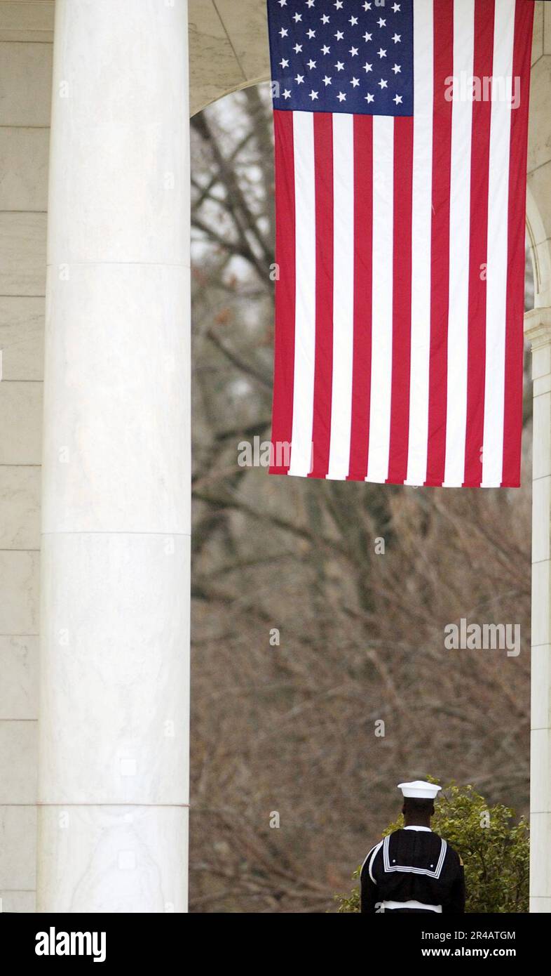 US Navy A member of the Navy Honor Guard stands under a large American ...