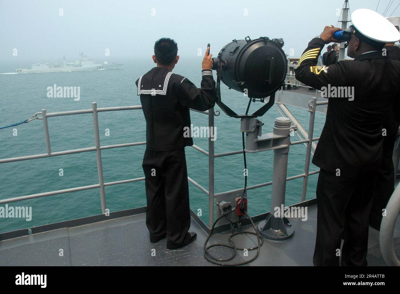 US Navy Quartermaster 2nd Class uses flashing light to communicate with ...