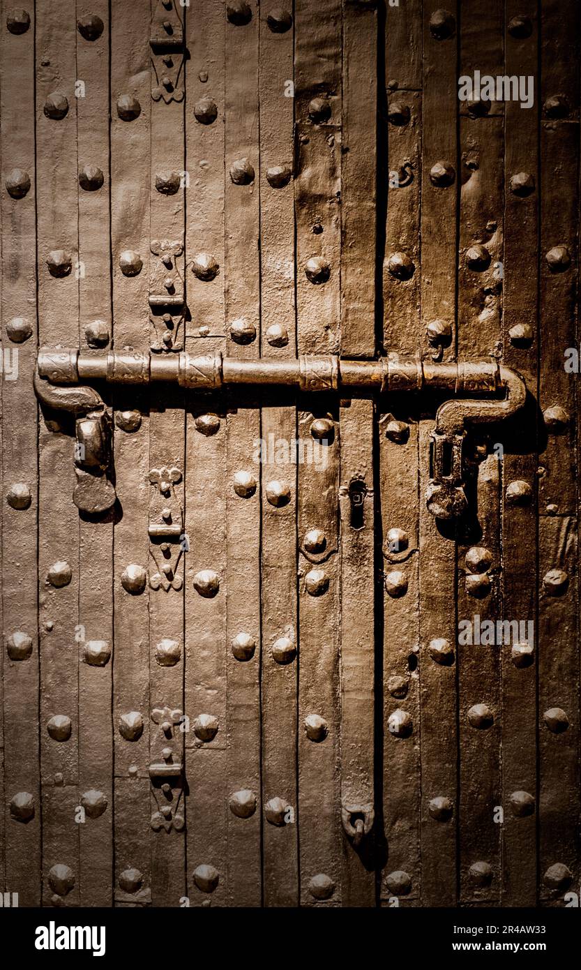 A wooden door with multiple handles and knobs in a dimly lit room Stock ...
