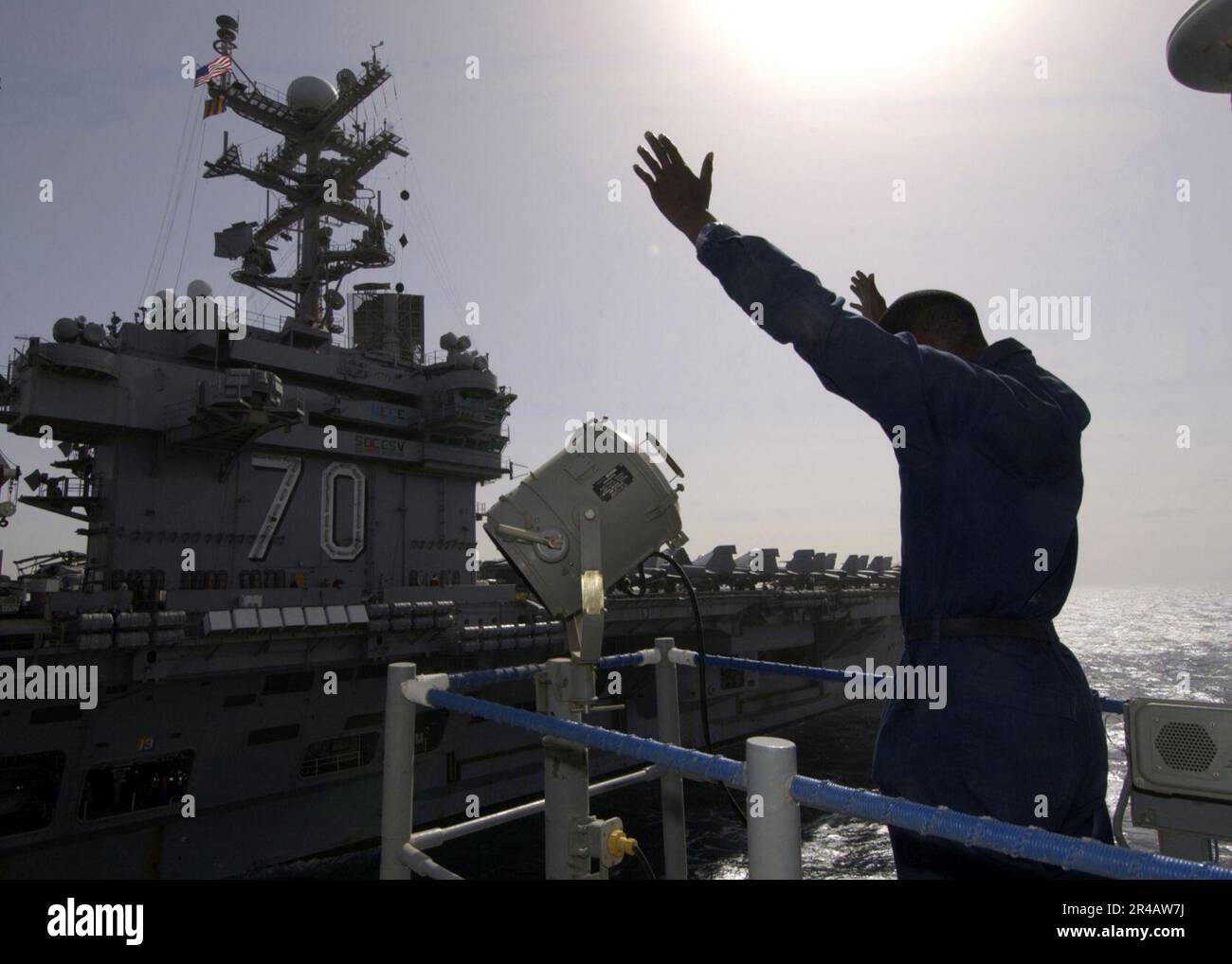 US Navy A Signalman uses semaphore to communicate via hand signals with ...