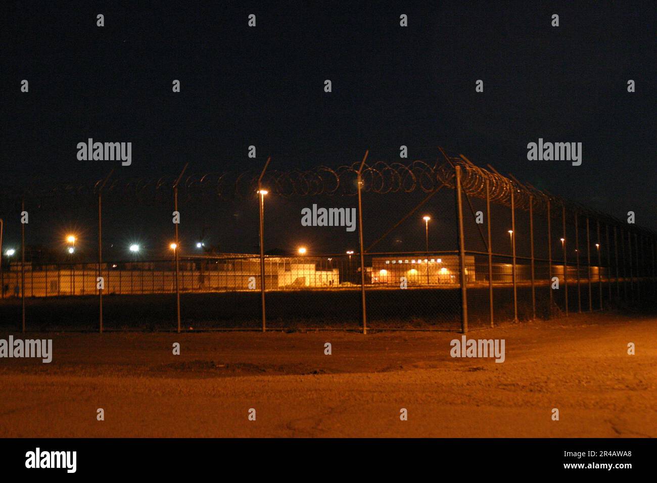 A steel security gate stands illuminated in the darkness outside of an ...