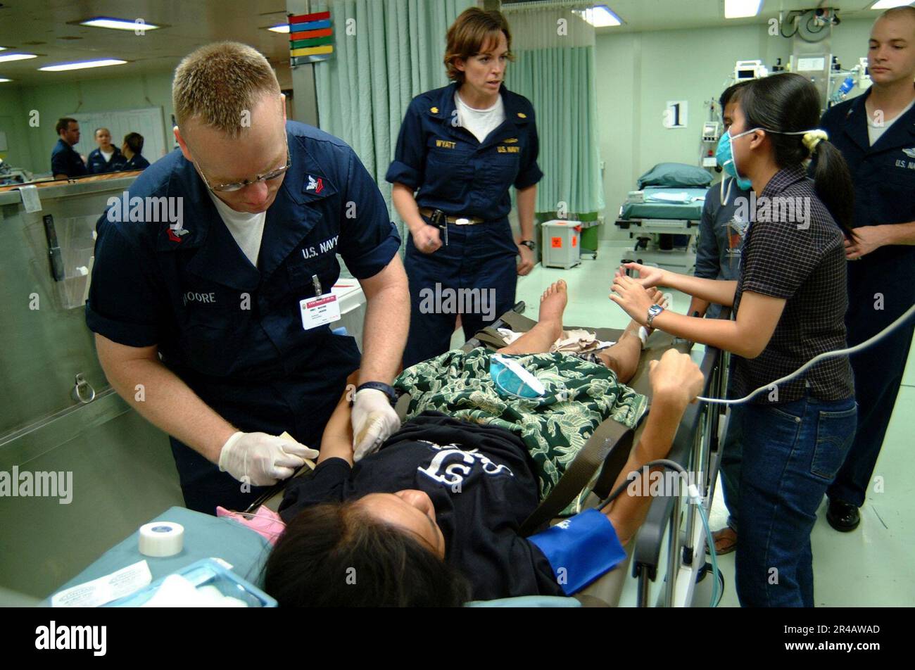 US Navy Hospital Corpsman 2nd Class prepares to put an IV in the arm of ...