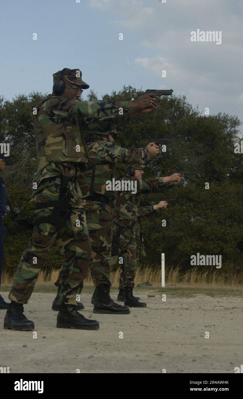 US Navy Photographer's Mate 1st Class left, takes aim during his 9mm ...