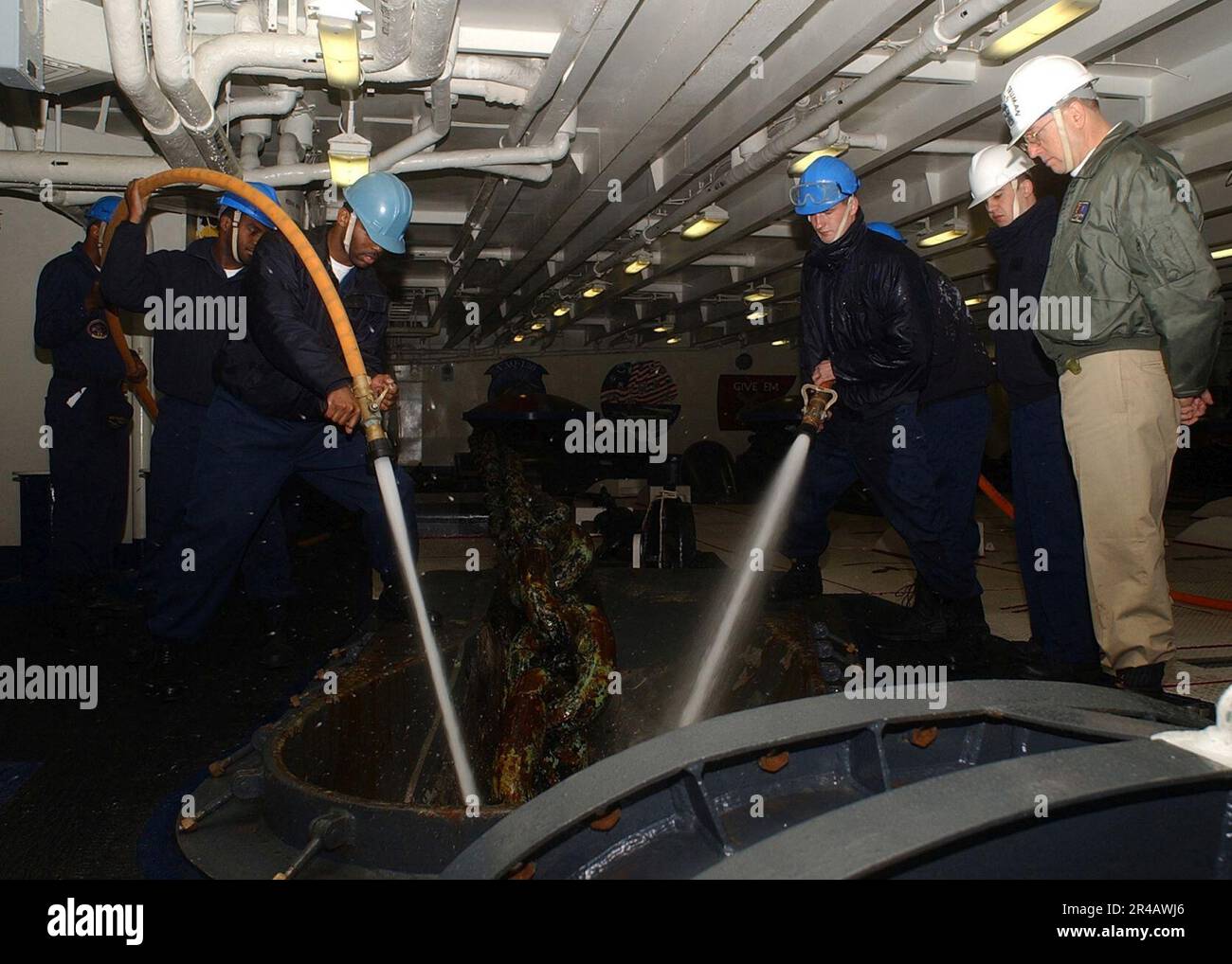 US Navy Deck Seamen spray down the anchor chain and anchor from the ...