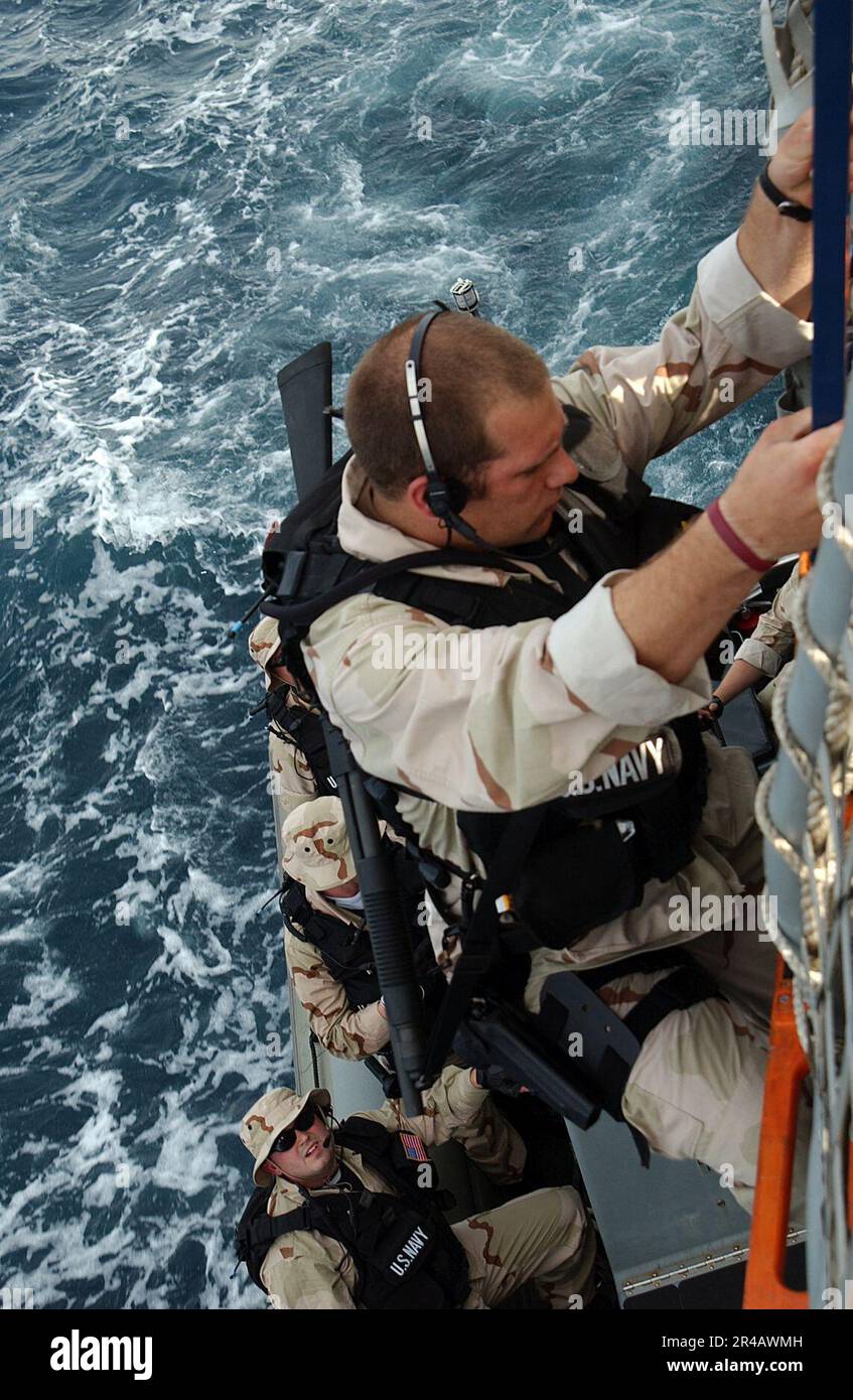 US Navy Damage Controlman 2nd Class climbs up the side of the Arleigh ...
