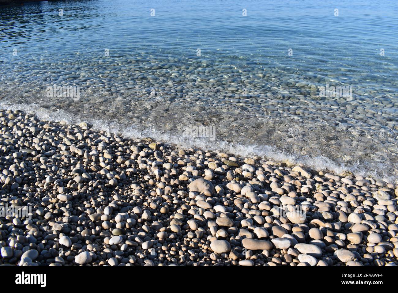 A scenic view of natural pebbles at the edge of a body of water, with ...