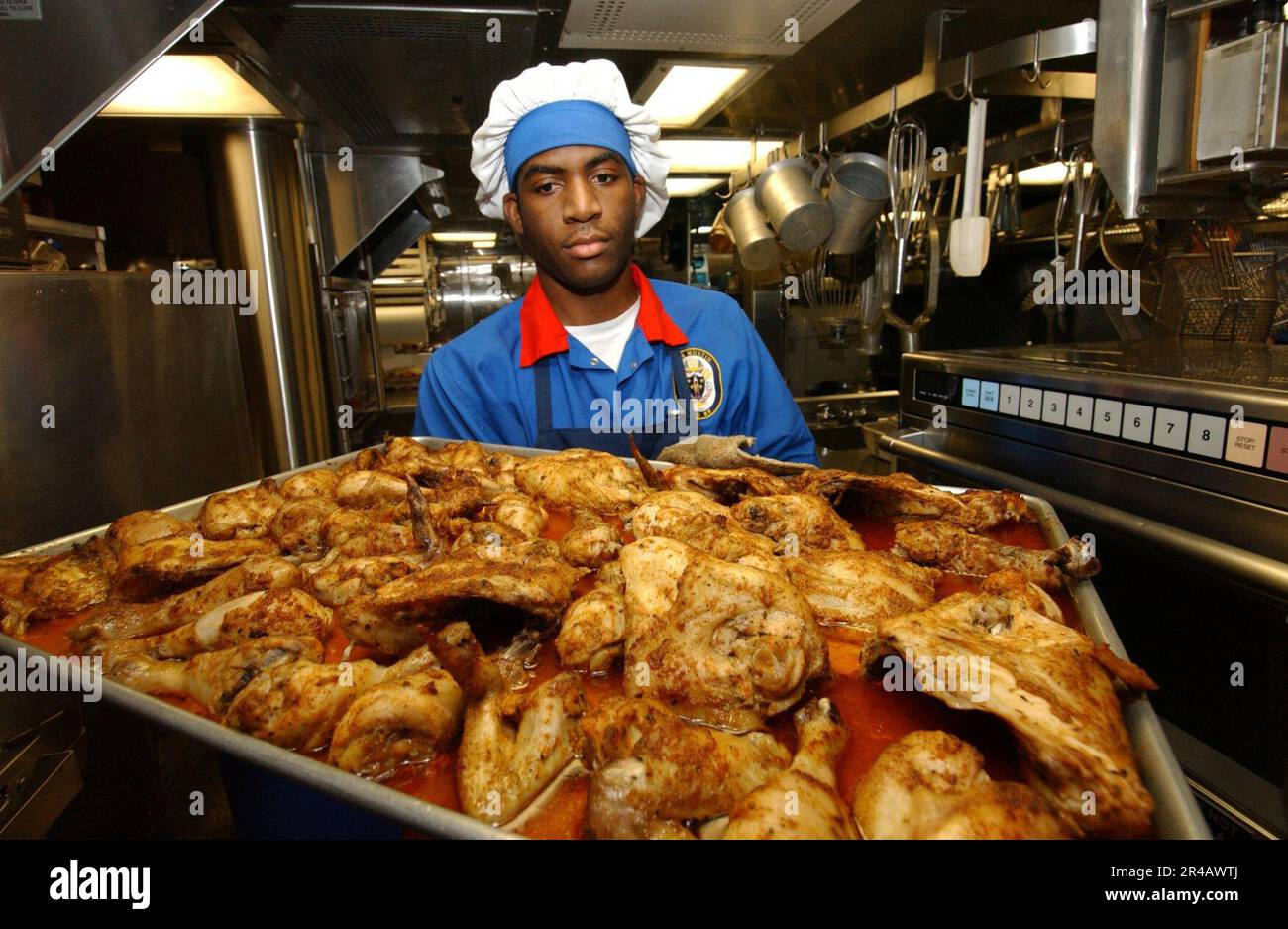 US Navy Culinary Specialist pulls chicken out of the oven for lunch ...