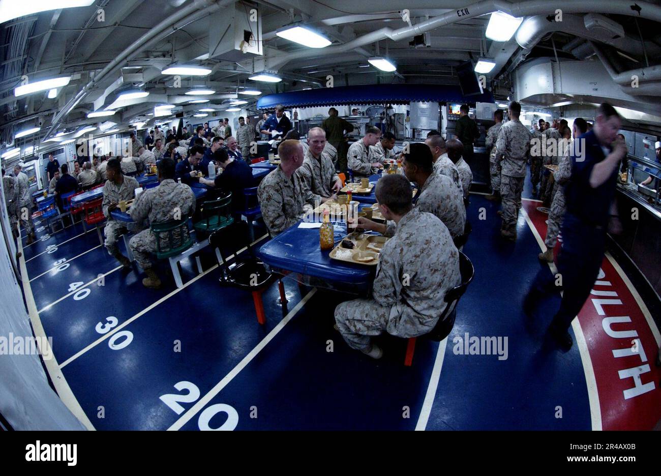 US Navy Marines and Sailors enjoy dinner on the mess decks onboard amphibious transport dock ...