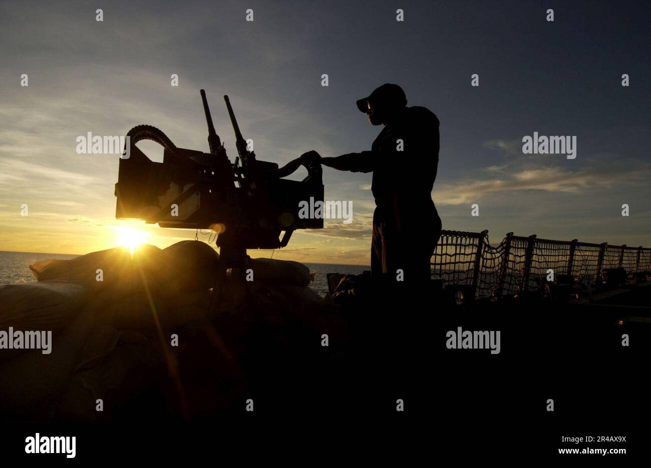 US Navy Gunner's Mate 2nd Class stands watch next to a twin .50 caliber ...
