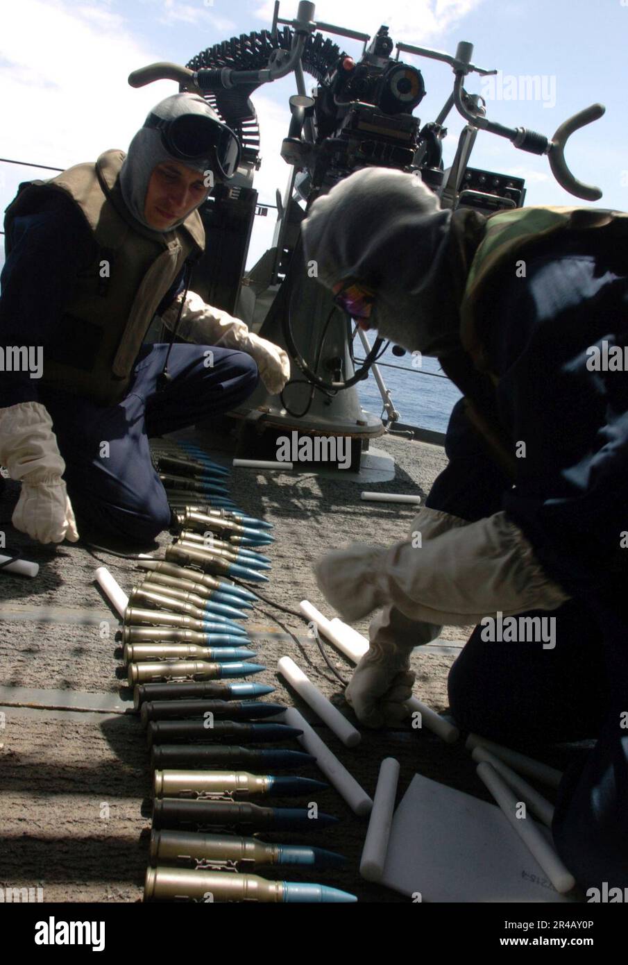 US Navy Gunner's Mate 2nd Class and Gunner's Mate Seaman feed-out a ...
