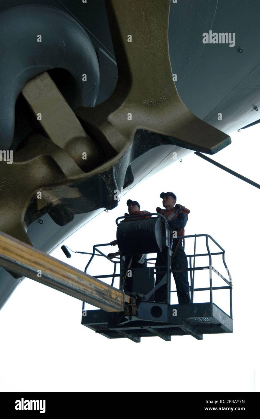 US Navy Sailors assigned to the Deck Department apply gold paint to one ...