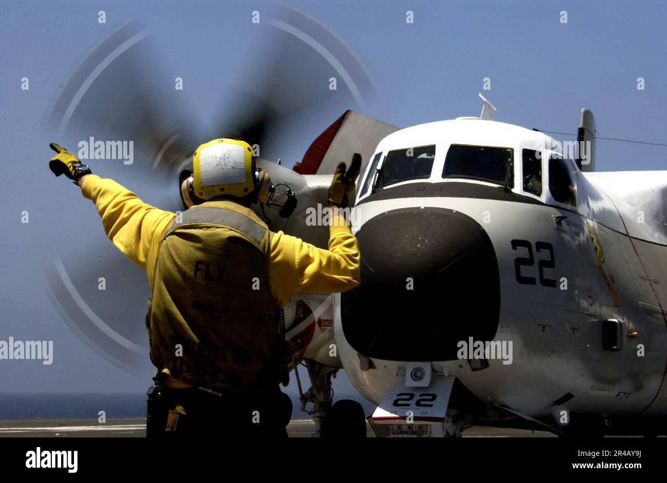 US Navy A flight deck handler directs a C-2 Greyhound attached to the ...