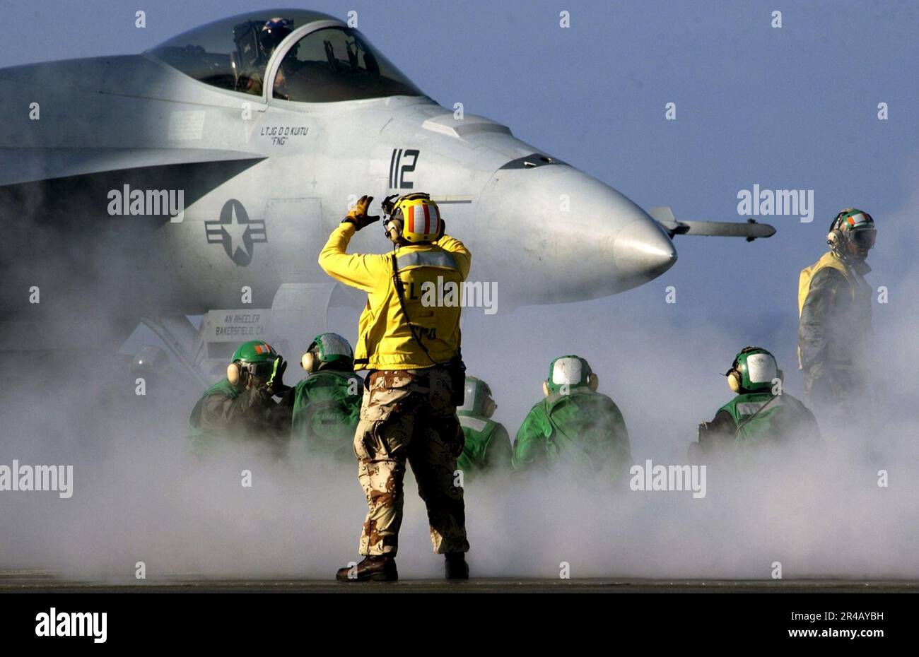 US Navy A flight deck handler directs an F-A-18E Super Hornet attached ...