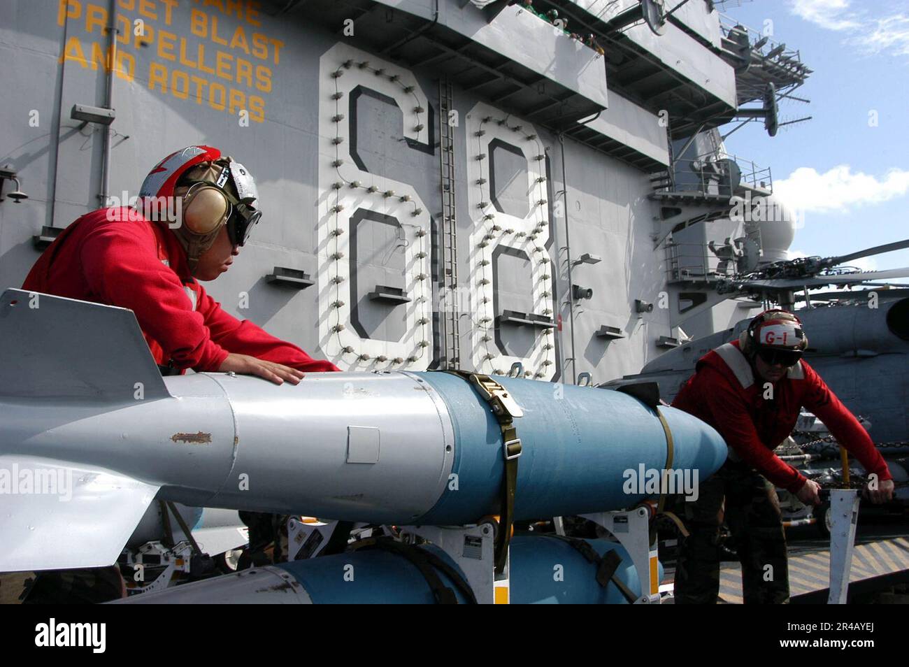 US Navy Aviation Ordnancemen assigned to the Weapons Department transfer inert general purpose ...