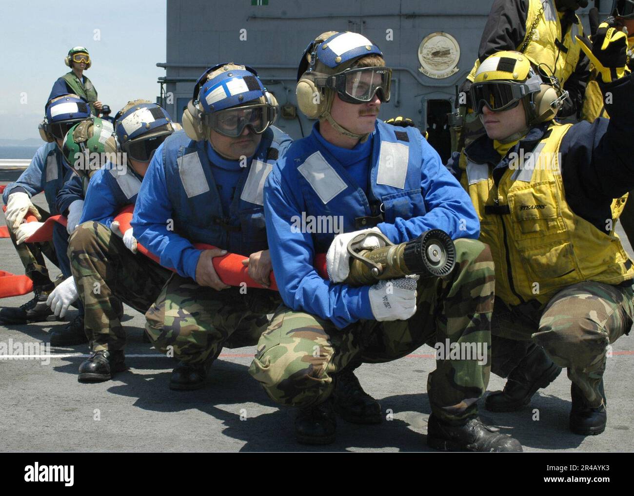US Navy Air department Sailors man a 2.5-inch fire hose during an ...