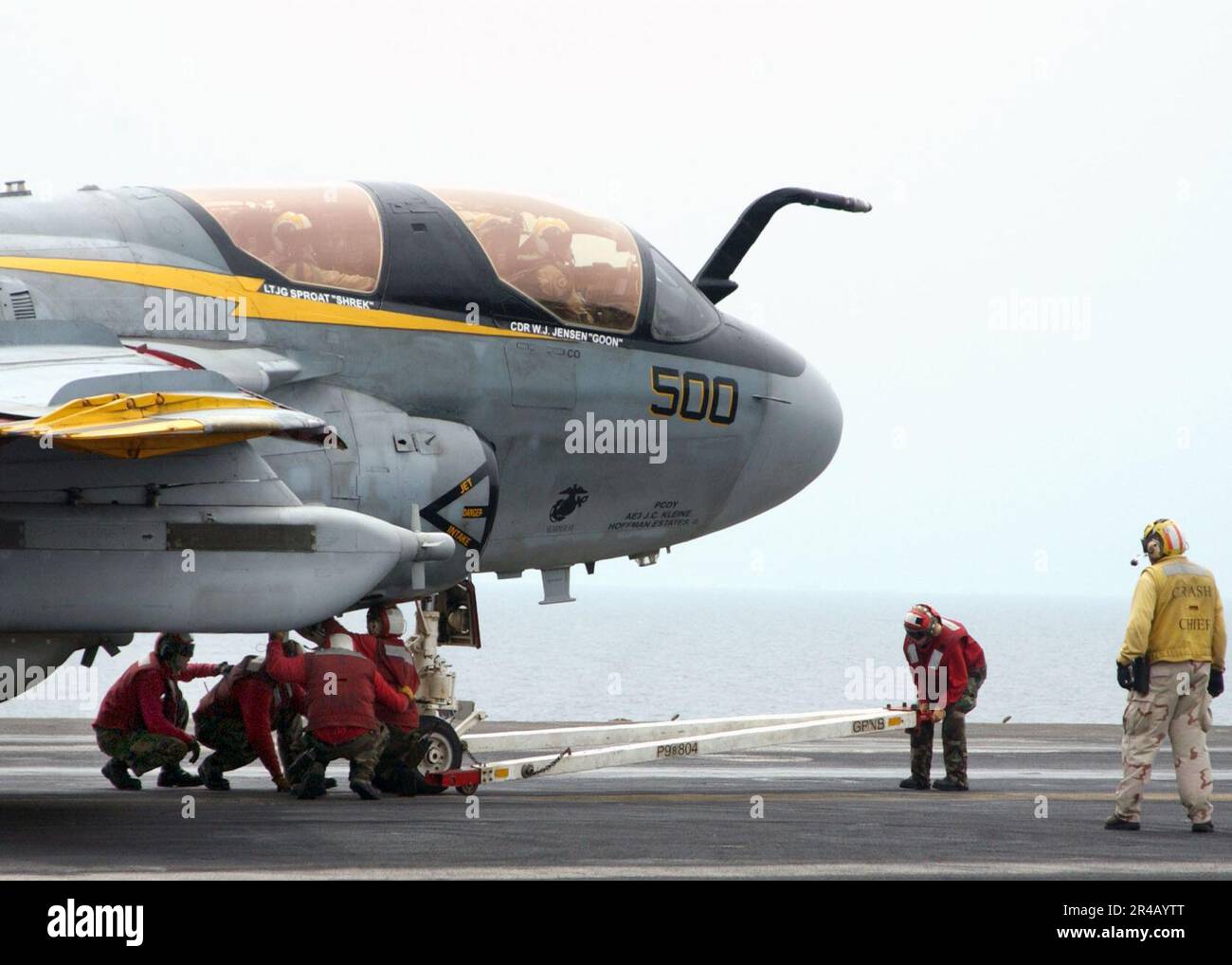 US Navy Crash and Salvage crew members attach a tow-bar to an EA-6B ...
